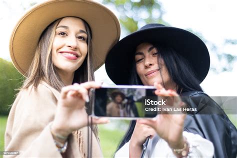 Two Stylish Friends Both Grabbing A Cell Phones To Take A Selfie Stock