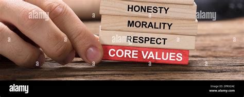 Businessman Holding Red Core Values Block Under Wooden Tower Stock