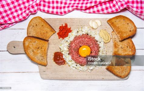 마늘 달걀 노른자 구운 빵 겨자 케첩 고추 양파를 곁들인 맛있는 생 소고기 스테이크 타르타르위에서 바라보는 체코 요리의 전형적인 변형입니다 체크 레드 키친 타월 건강한