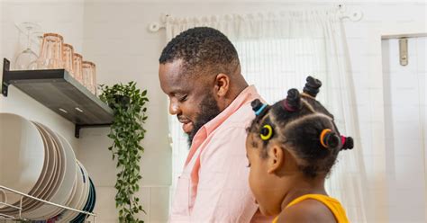 아프리카 아버지는 어린 딸에게 부엌 카운터의 싱크대에서 설거지를 가르치고 저녁 식사를 한 후 함께 이야기를 나눕니다 행복한