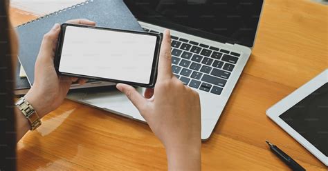 사무실 책상에 모형이 있는 스마트폰을 들고 있는 위의 사진은 여성입니다 그래픽 디스플레이 몽타주를 위한 빈 화면 휴대폰 사진 Unsplash의 모델 개체 이미지