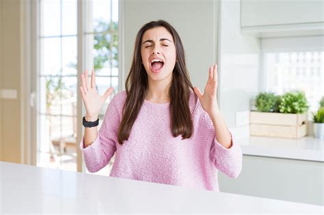 아름 다운 젊은 여성이 분홍색 스웨터를 입고 미친 소리와 소리 공격적인 표정과 팔을 제기 했다 좌절 개념입니다 가정 생활에 대한