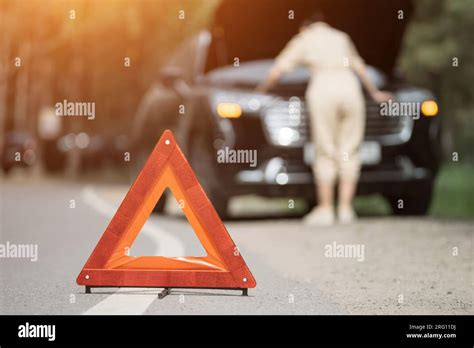 warning triangle against woman driver trying to fix defect in engine