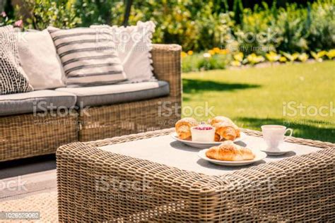 베이 지 색상 고리 버들 세공 테이블 그리고 정원에서 화창한 오후 동안 현관에 긴의 자 크루아상과 커피 테이블에 제공 됩니다