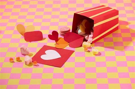 노란색과 분홍색 체크 무늬 배경에 귀여운 선물 상자가 쓰러지고 컬러 종이 하트 사탕 케이크 마시멜로 등 사랑스러운 아이템이 떨어집니다 발렌타인 데이 장식에 대한 아이디어 0