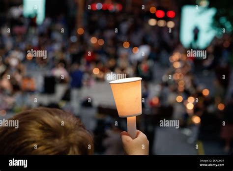 A Boy Holds A Candle Up To The Crowd During A Candlelight Vigil In