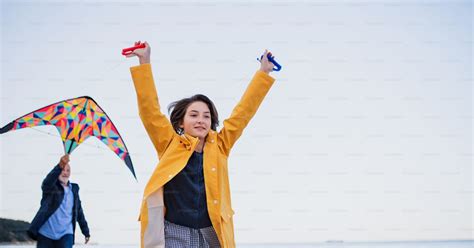 10대 초반 소녀와 그녀의 할아버지가 모래사장에서 연을 가지고 노는 낮은 각도의 모습 사진 Unsplash의 사진술 이미지