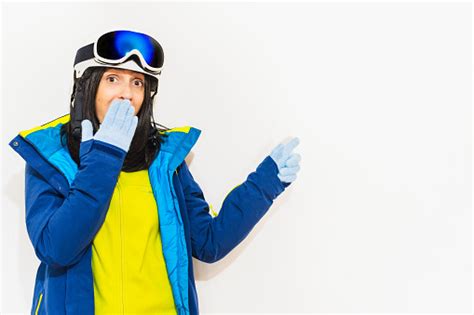 따뜻한 패딩 윈드 브레이커 재킷 모자 스키 고글 마스크 포인트 검지 손가락을 입고 스키어 젊은 여자는 복사 공간 빈 공간 여행 휴식을 주말 겨울 시즌을 보냅니다 흰색 배경에
