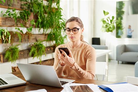 매력적인 사업가 문자 그녀의 노트북 뒤에 사무실 책상에 앉아있는 동안 메시지 여자 사업가에 대한 스톡 사진 및 기타 이미지