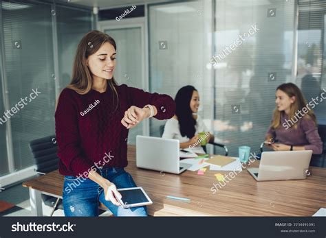 Checking Time On Wristwatch While Working On Laptop In Modern Workspace Stock Photos Images