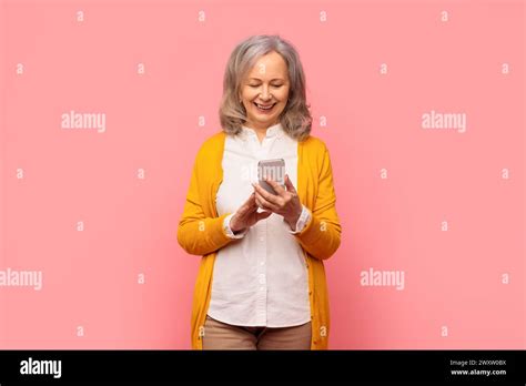 European Senior Lady Scrolling Through Messages On Her Smartphone
