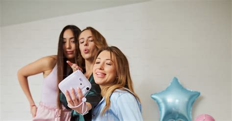 노래방 무선 마이크를 가진 여자와 그녀의 두 친구가 홈 파티에서 셀카를 찍고 있다 사진 Unsplash의 촬영 이미지