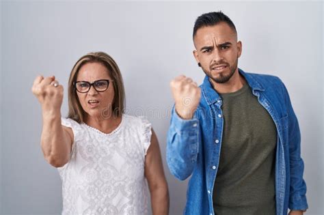 Hispanic Mother And Son Standing Together Angry And Mad Raising Fist
