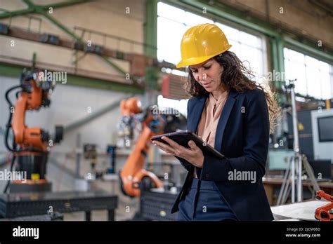 Automation Female Engineer With Tablet For Programming Robotic Arm In