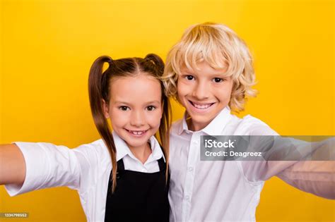사진 두 명의 긍정적 인 여학생 촬영 셀카 이빨 미소 착용 학교 유니폼 고립 된 노란색 색상 배경 2명에 대한 스톡 사진 및