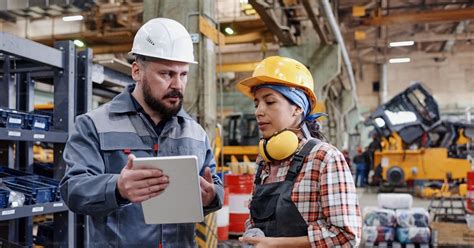공장에서 젊은 여성 동료에게 새로운 기술 프로젝트를 발표하는 태블릿을 가진 수염 난 성숙한 엔지니어 사진 Unsplash의
