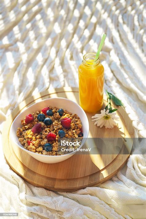 그 라 놀라와 열매 라즈베리 흰 그릇에 블루 베리와 부드러운 아침 햇빛에 아늑한 니트 흰색 격자 무늬에 둥근 나무 쟁반에 신선한 오렌지 주스와 건강 한 아침 식사 0명에