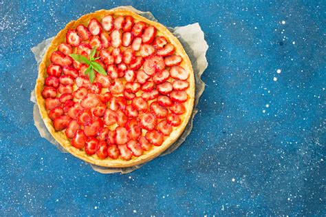 커스터드 바닐라 크림으로 채워진 신선한 홈메이드 딸기 쇼트크러스트 타르트 파이 트렌디 한 팬텀 블루 코스모스 배경에 슬라이스