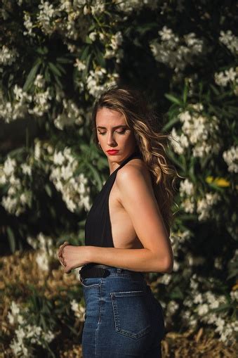 화창한 날에 푸른 나무의 흐릿한 배경에 포즈를 취하는 젊은 백인 여성의 수직 근접 촬영 갈색 머리에 대한 스톡 사진 및 기타