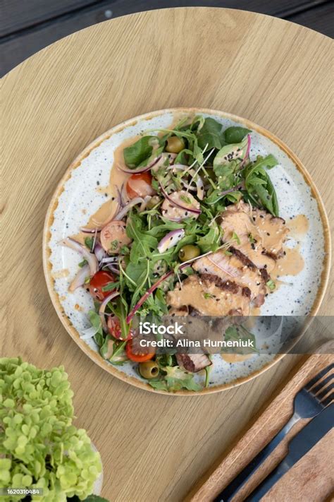 채소에 송아지 고기를 얹은 접시 야채와 올리브를 곁들인 견과류 소스 나무 탁자 위에 올려진 접시 0명에 대한 스톡 사진 및 기타 이미지 Istock