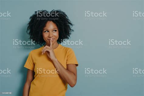 입술 근처에 손가락으로 Shhh 사인을 보여주는 쾌활한 아프로 소녀 파스텔 블루 배경 위에 서 곱슬 머리에 대한 스톡 사진 및 기타 이미지 Istock