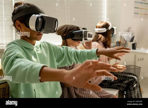 Contemporary Schoolgirl And Her Two Classmates In Vr Headsets Touching