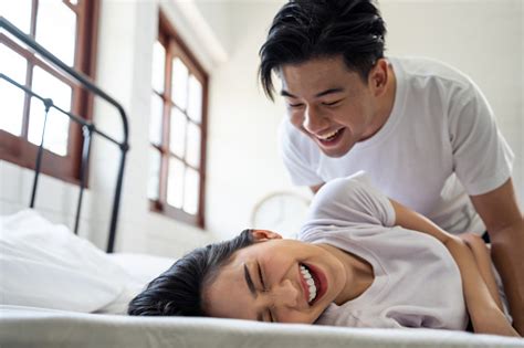 아시아의 매력적인 남자는 침대에 누워있는 동안 여자 친구를 간지럽 힙니다 잠옷을 입은 매력적인 아름다운 새 부부는 집에서 침실에서 이른 아침 활동을 즐깁니다 가족 관계 개념