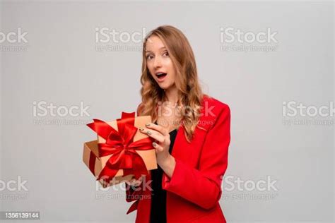 빨간 활로 장식 된 선물 상자를 들고 매력적인 젊은 여성 대망의 생일 선물을 즐기는 여성 꿈이 실현됩니다 스튜디오 샷 회색 배경 25 29세에 대한 스톡 사진 및 기타