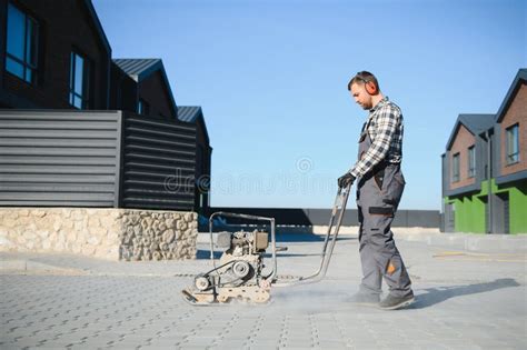 Male Worker Using Vibratory Plate Compactor To Firm Soil At Worksite