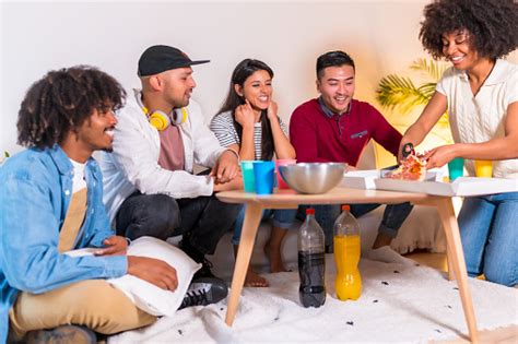 소파에 앉아 피자를 먹고 홈 파티에서 청량 음료를 마시는 다민족 친구들 피자를 자르고 나눠주는 소녀 20 24세에 대한 스톡 사진 및 기타 이미지 Istock