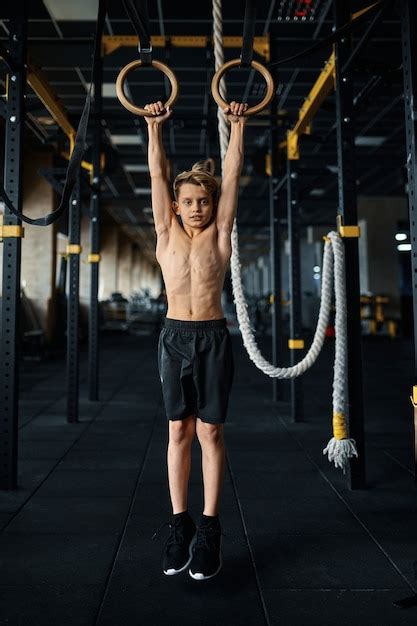 Premium Photo Athletic Boy Doing Exercise On Rings In Gym Youngster