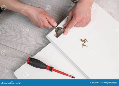 Assembling Furniture A Worker Inserts A Hinge Into A Wooden Closet Door Adjustment Of Fittings