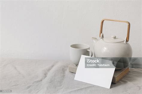 아침 식사 정물 장면 커피 한 잔 오래된 책에 도자기 찻 주전자 빈 인사말 카드 초대 모형 베이지 색 린넨 식탁보 흰색 벽 배경 중립적 인 아침 라이프 스타일 구성 0명에
