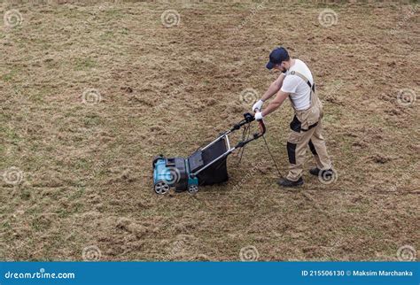 Scarifying Lawn With Scarifier Man Gardener Scarifies The Lawn And Removal Of Old Grass Stock