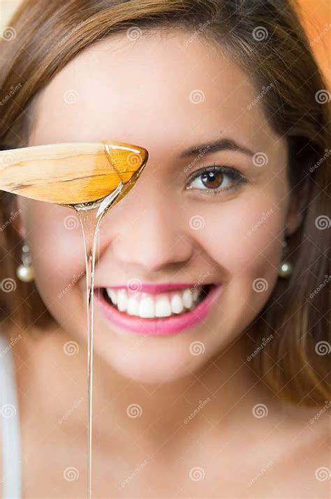 Young Brunette Woman Sitting Holding Wooden Knife With Golden Honey