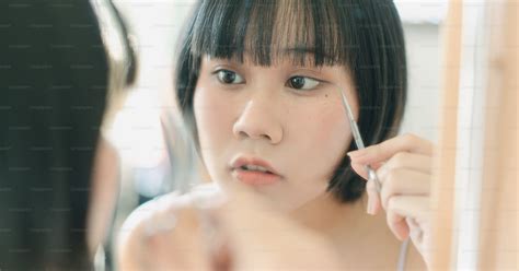 격리 라이프스타일은 집에 머무르는 개념입니다 젊은 성인 아시아 여성 자기 절단 앞머리 가위로 거울을 보는 눈 자연 채광이 있는 낮의 배경 사진 Unsplash의