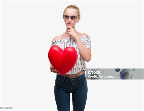 금발 십 대 여 자가 질문 매우 혼란 스 러 워 아이디어에 대해 레드 심장 심각한 얼굴 생각 들고 하트 모양에 대한 스톡 사진 및 기타 이미지 Istock