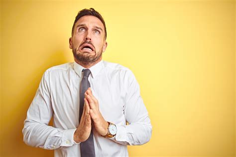 노란색 고립 된 배경에 우아한 흰색 셔츠를 입고 젊은 잘 생긴 사업가 구걸과 함께 희망 표정과 함께 기도 매우 감정적이고 걱정 용서를 구함 종교 개념 감정에 대한 스톡 사진