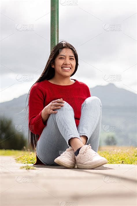 年轻微笑的拉丁女孩坐着看着相机