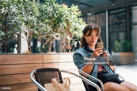 데님 재킷을 입고 커피 숍에서 전화를 사용하는 행복한 아시아 중국 여성 보도 카페에서 행복하고 미소 짓기 야외 30 34세에 대한 스톡 사진 및 기타 이미지 Istock