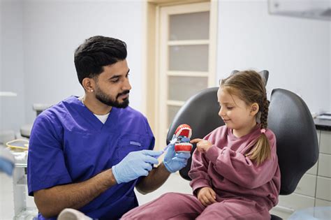 어린 미취학 소녀에게 양치질 방법을 보여주는 젊은 자신감 있는 수염 난 소아 치과 의사 20 24세에 대한 스톡 사진 및 기타 이미지 20 24세 2명 4 5세