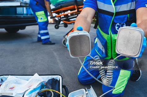 구급차 근처에서 사상자와 소생술을 구출하는 동안 제세동기 패드를 손에 들고 Ems 구급 대원 응급 의료 서비스 제세동기에 대한