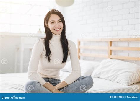 Young Beautiful Woman Smiling And Sitting On Bed At Home Stock Image