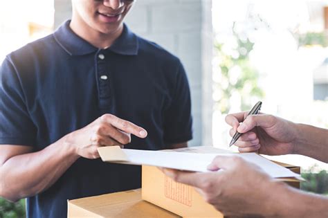 소포 상자 받는 사람 및 서명 양식 포스트 배송 택배 홈 배달 서비스 및 서비스 마인드에서 배달 패키지의 영수증을 서명 하는 젊은 소유자에 게 배달 메일 남자 교통수단에