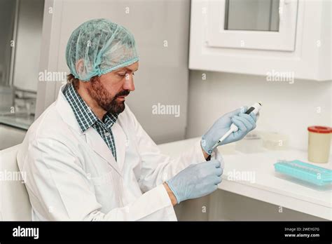 Male Scientist In Uniform Is Using Micropipette For Biochemical Test Analysis In Medical