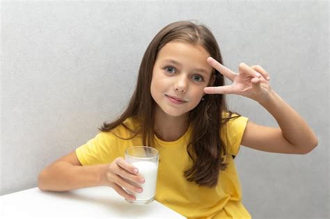 Retrato de niña feliz bebiendo leche en la mesa en la cocina Foto Premium