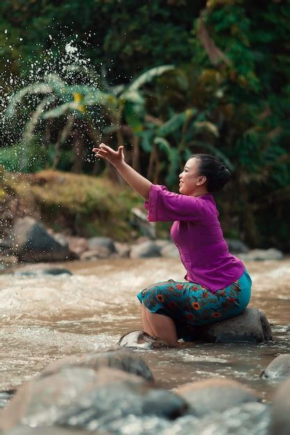 Premium Photo Indonesian Woman Sitting On A Small Rock And Playing