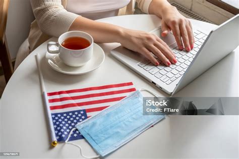여자 관광객 은 노트북에서 일하는 커피 한 잔과 함께 아침 식사를합니다 미국의 국기 카페의 테이블에 의료 보호 얼굴 마스크 공공 장소에서 박테리아와 바이러스로부터 보호 개념