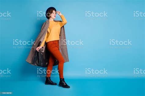 예쁜 아가씨의 전신 프로필 사진 해외 룩 쇼핑 센터 쇼핑몰 상점 착용 캐주얼 롱 그레이 코트 풀오버 바지 모자 신발 고립 된 블루 컬러 배경 갈색 머리에 대한 스톡 사진 및