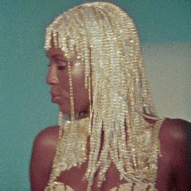 A Woman With Long Blonde Hair And Beads On Her Head Is Looking Away